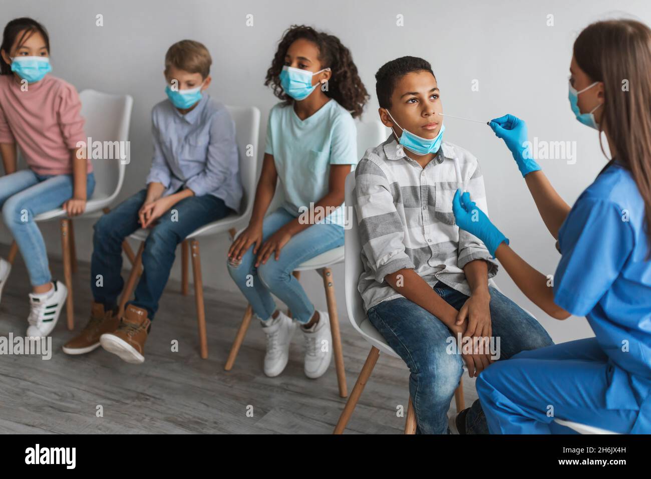 Medical Worker Making PCR Test For Kids Sitting In Clinic Stock Photo ...