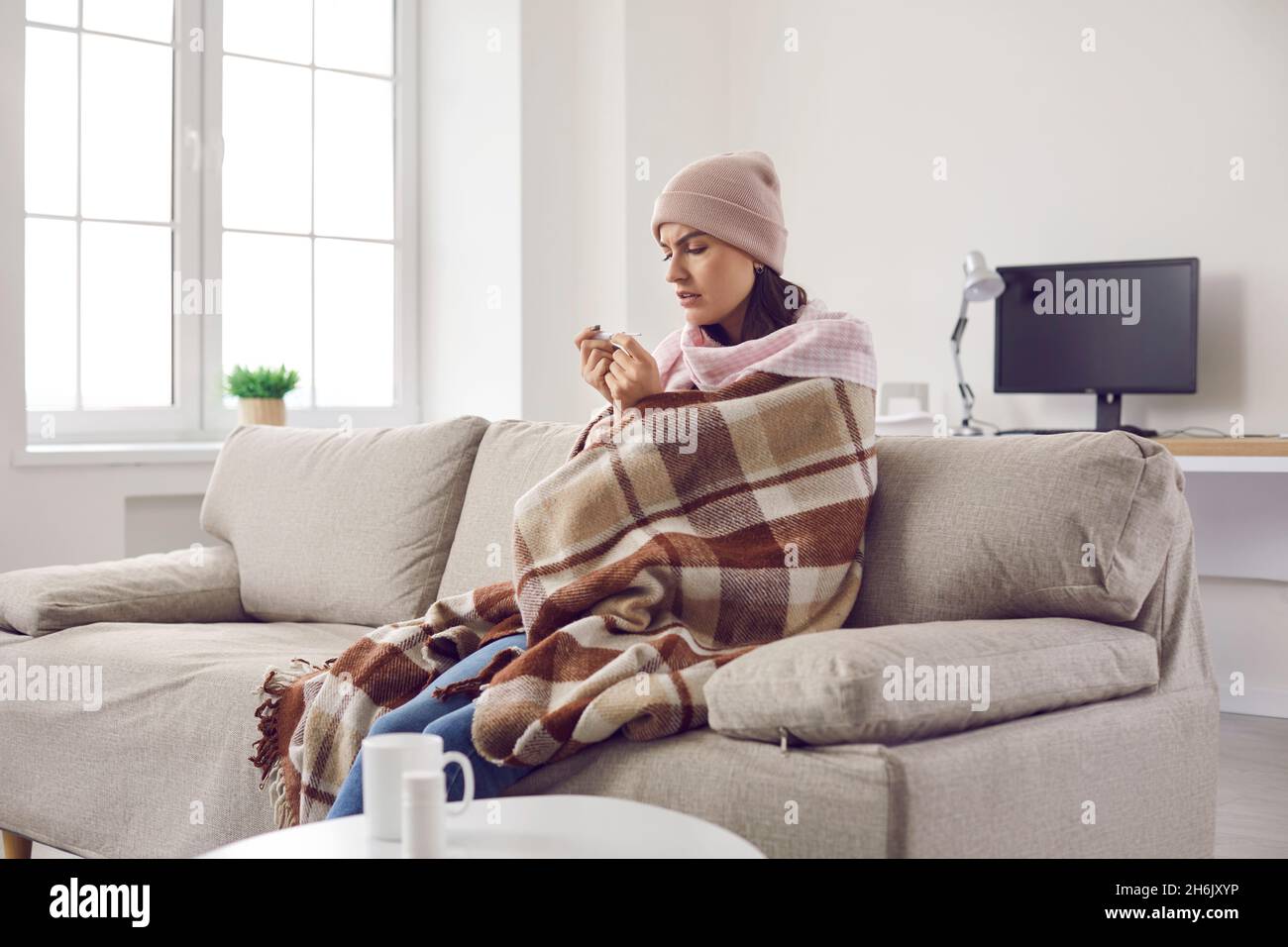 Woman who has fever due to cold or flu sitting on sofa at home and ...