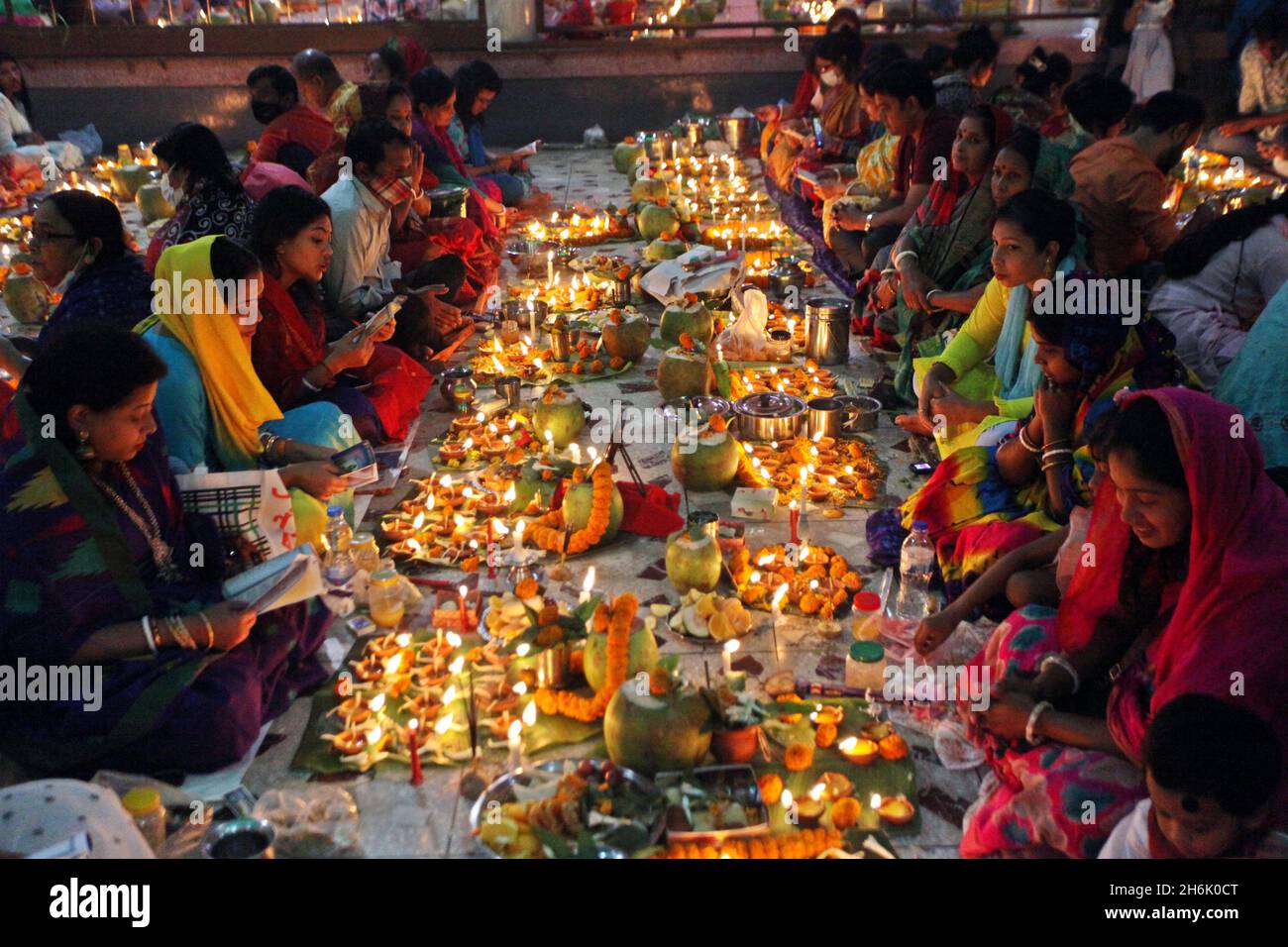 Hindu devotees sit with oil lamps and pray at the Shri Shri Lokanath ...