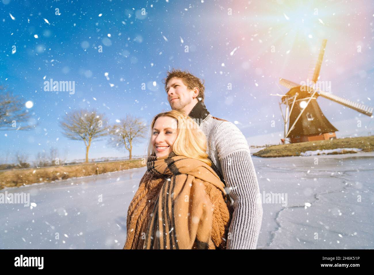 Loving couple having fun on ice in typical dutch landscape with ...