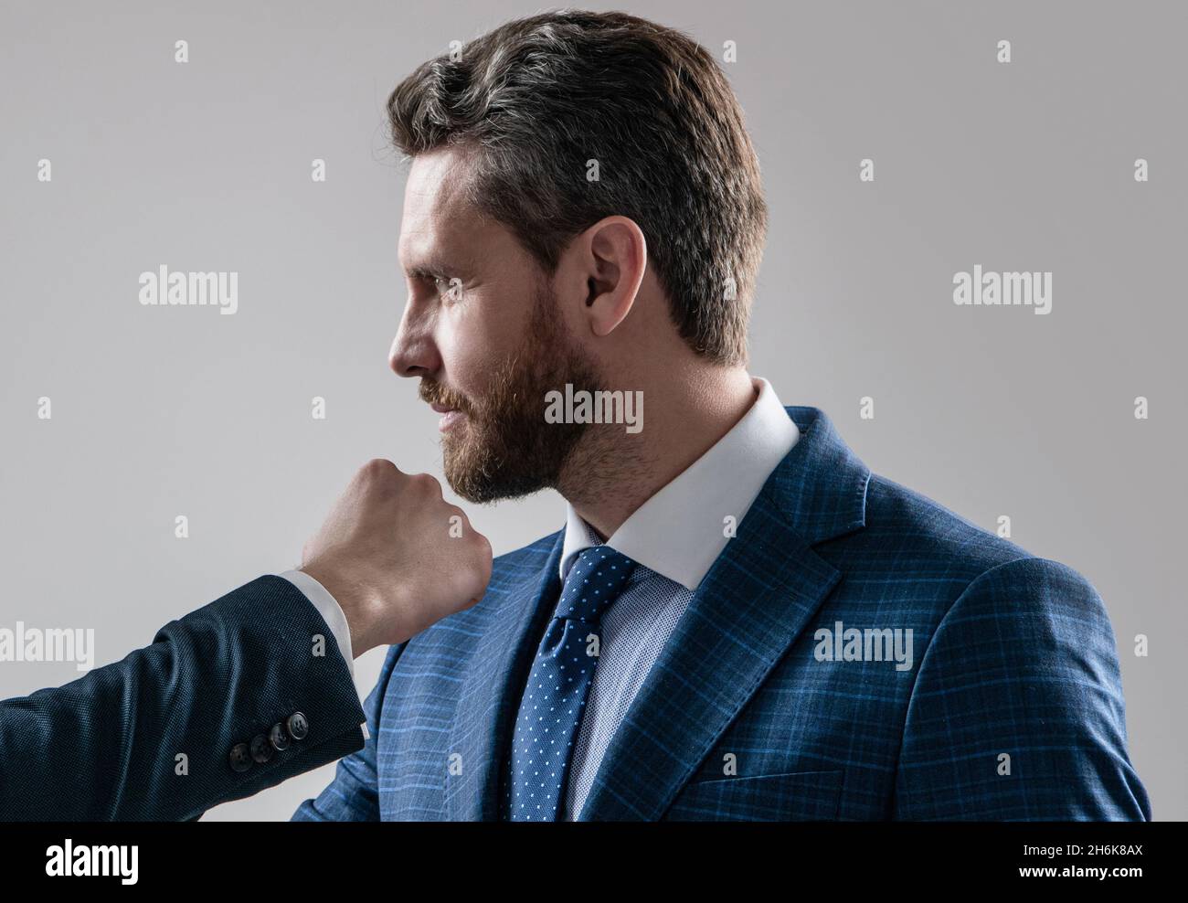 Professional man manager taking male fist punch in face grey background ...