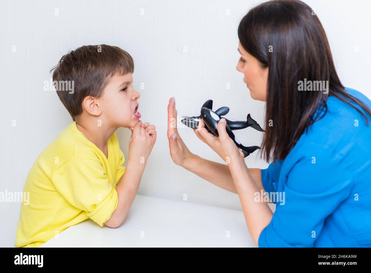 Beautiful woman speech therapist teaches boy the correct pronunciation ...