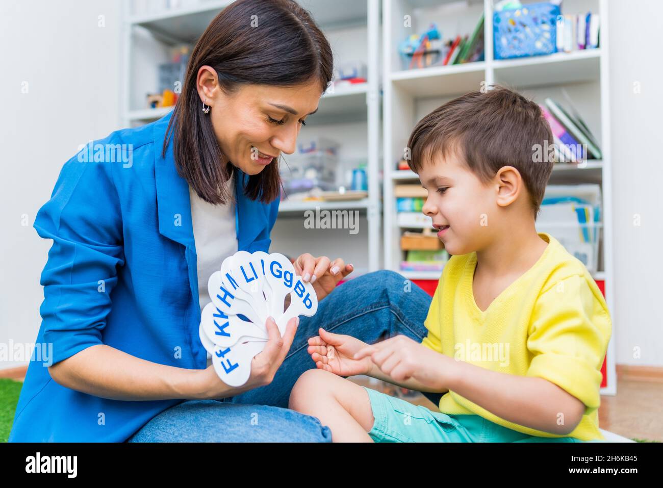 A cute child with a speech therapist is taught to pronounce the letters ...