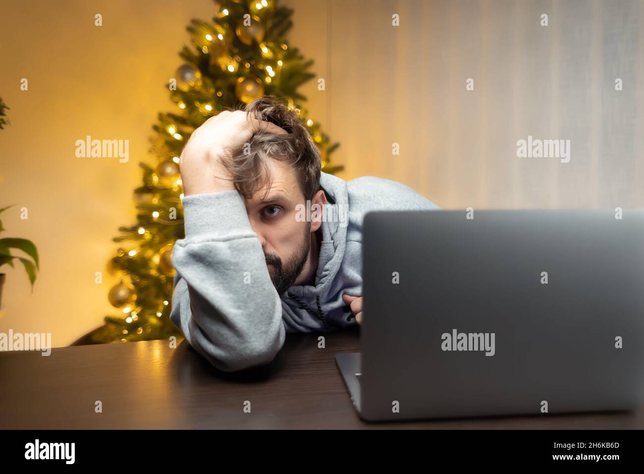 on Christmas night, a man bent over a computer, tired from work Stock ...