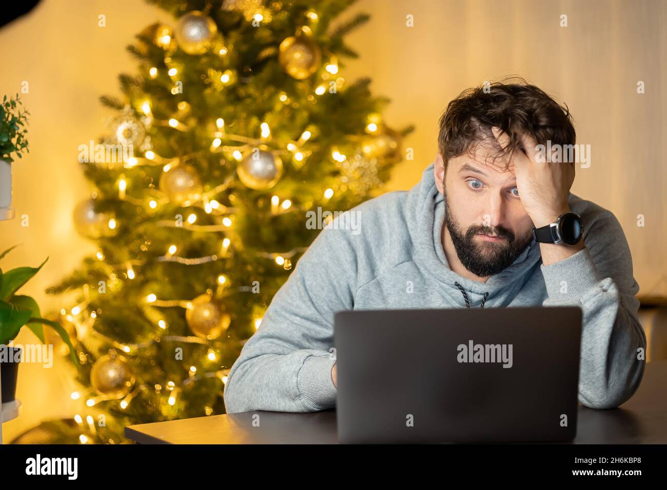 a disappointed man sits in front of a computer on New Year's Eve in the ...