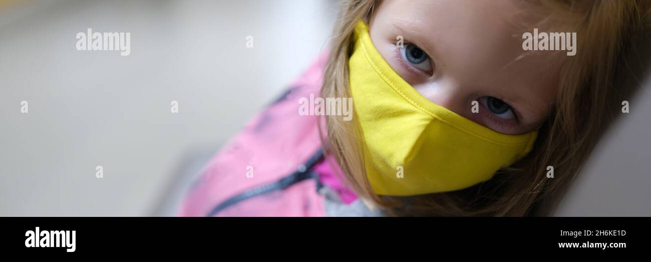 Little girl in yellow protective medical mask sitting in hospital ...