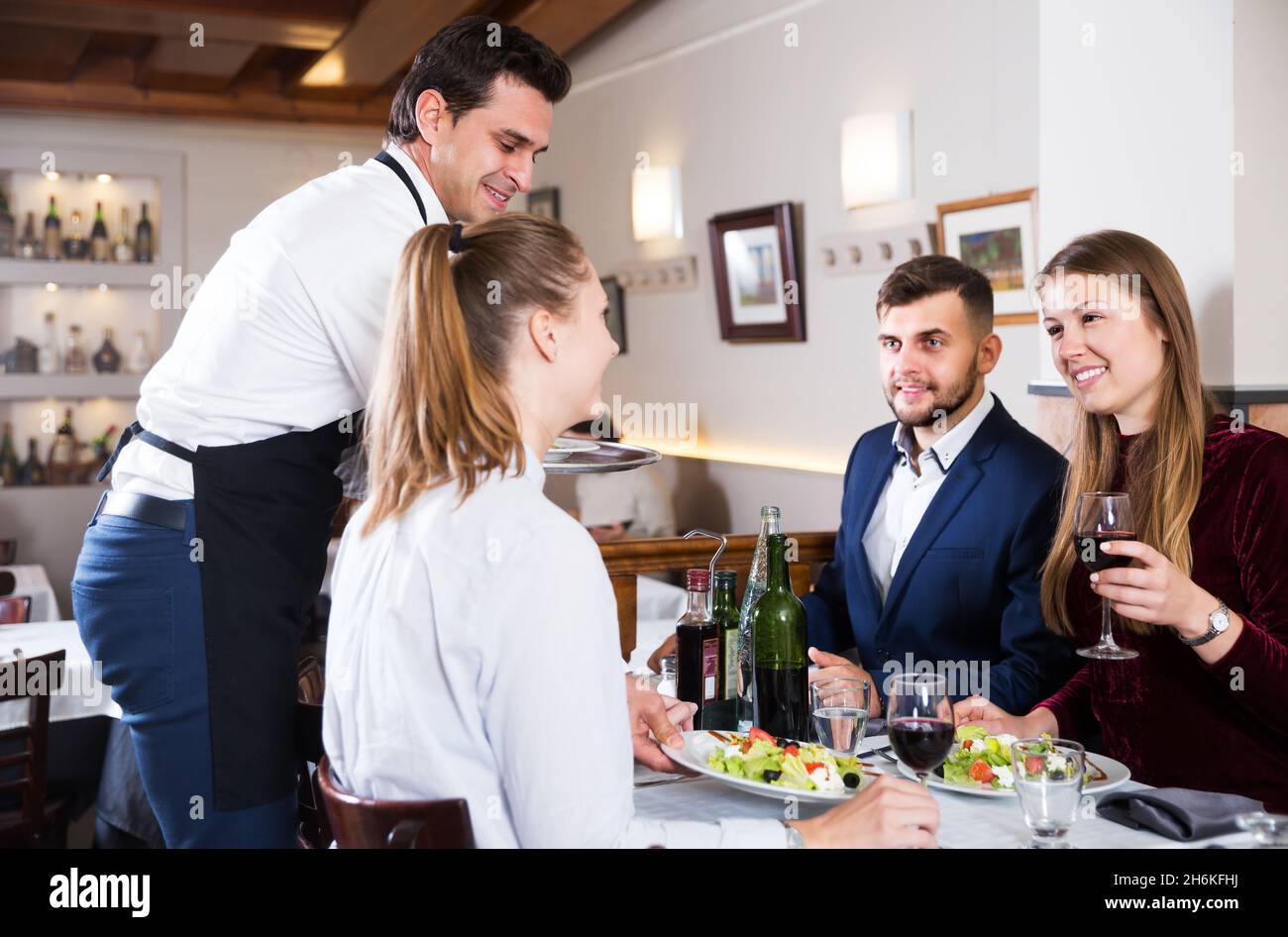 Waiter bringing dishes to guests Stock Photo - Alamy