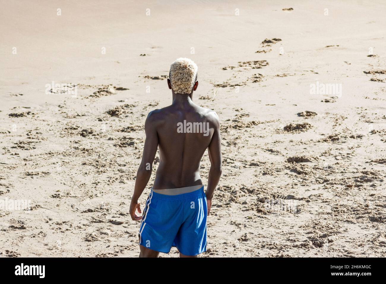 Young model playing sand football on the beach under strong summer sun ...