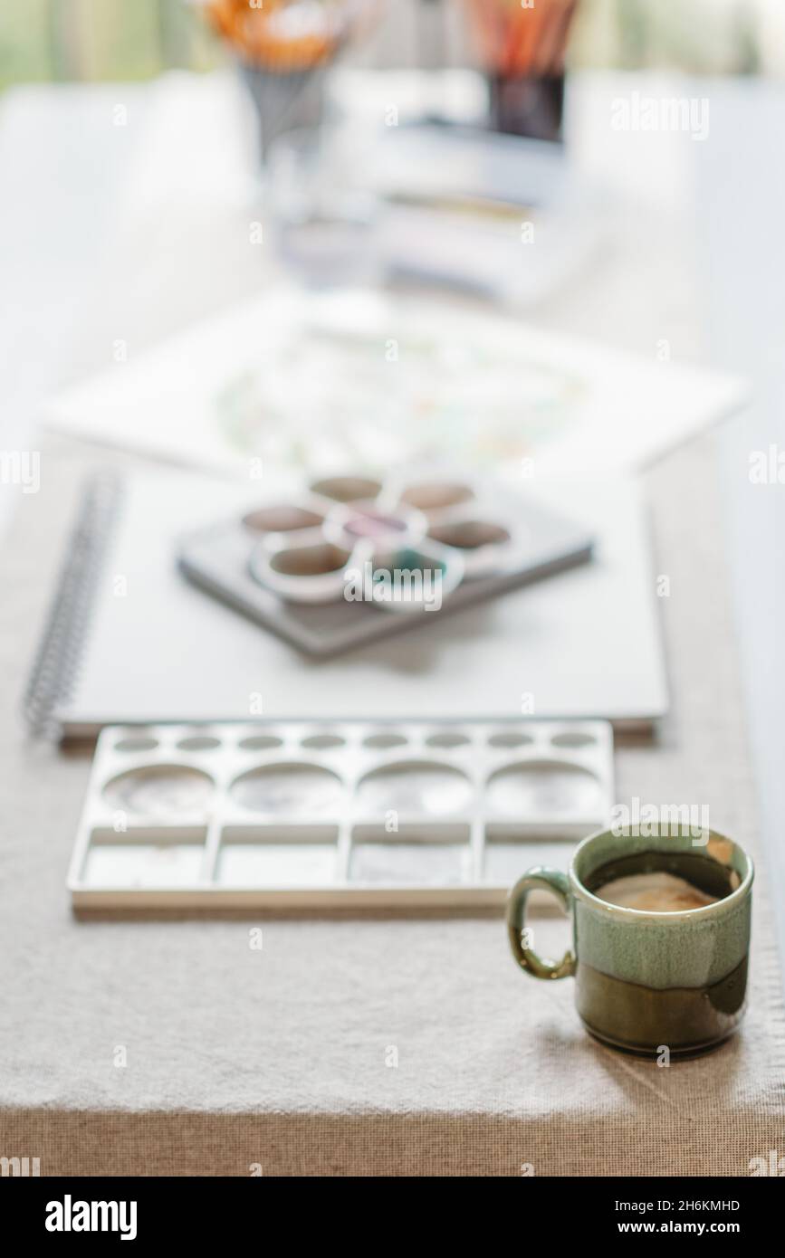Cup of coffee, watercolor palette, notebook, and a painting by two ...