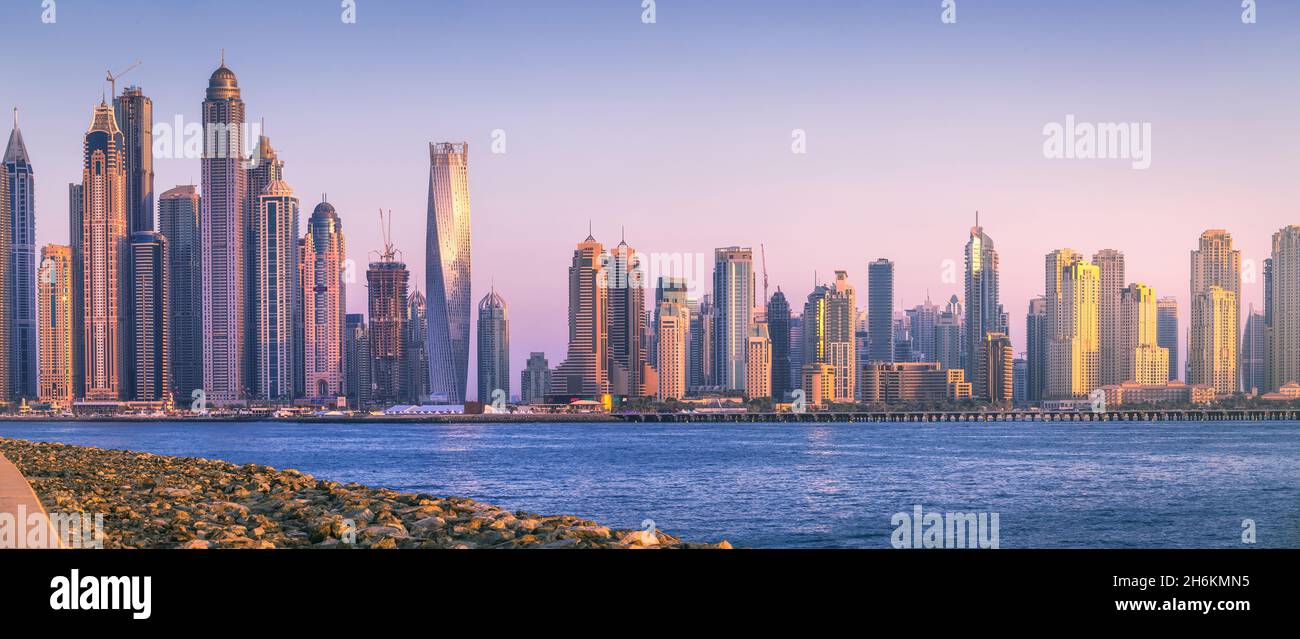 Modern buildings with gold reflection of sunset on Dubai Marina bay ...