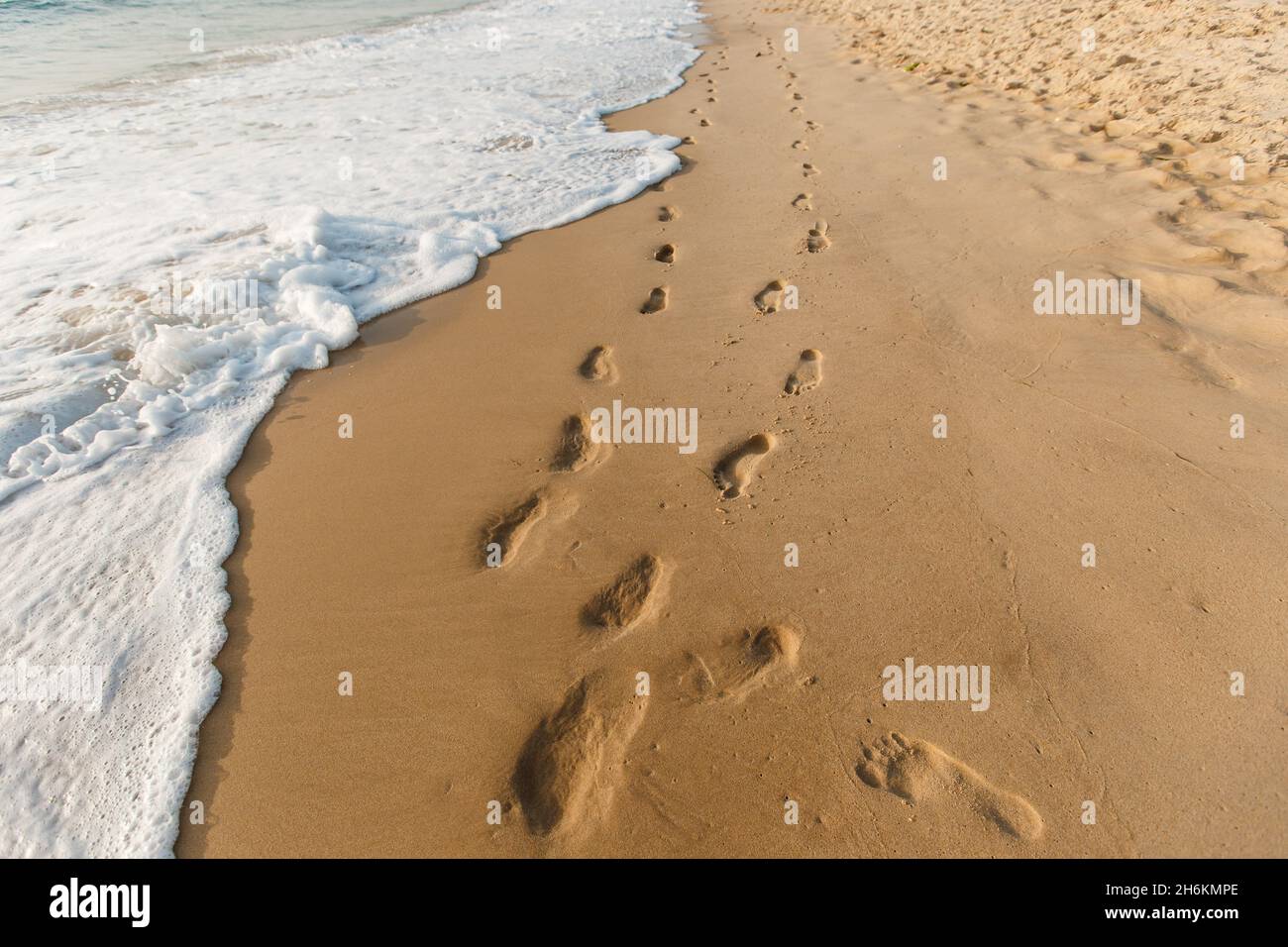 Two footprints ways on the sand. Ocean waves wash away people's tracks ...