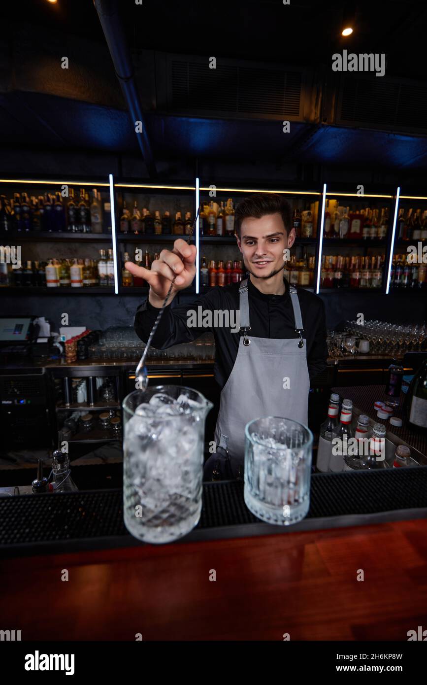 Barman stirring ice cubes in cocktail glass with spoon Stock Photo - Alamy