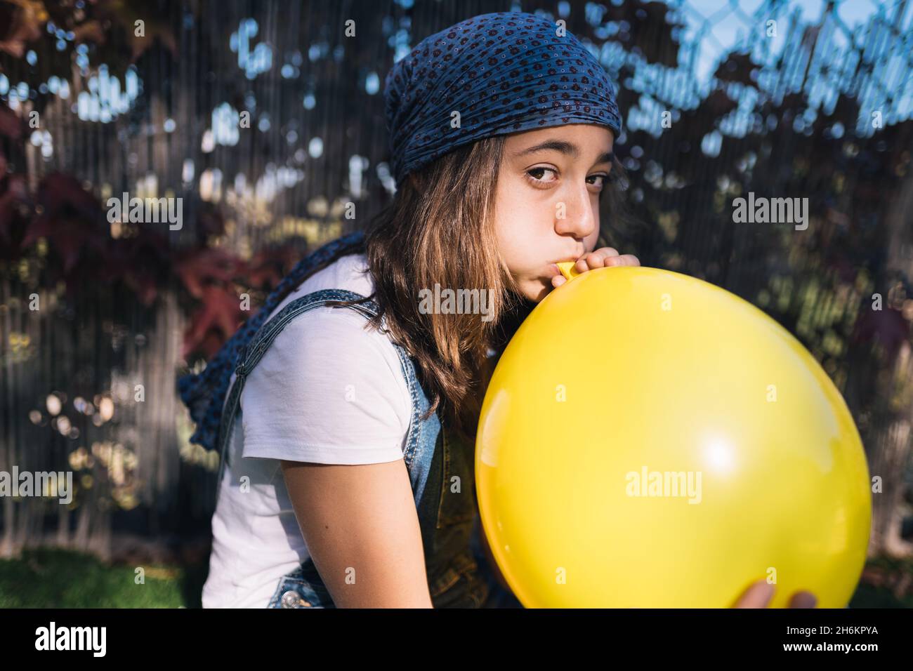 Teenage girl with a headscarf and long brown hair blowing up a huge ...