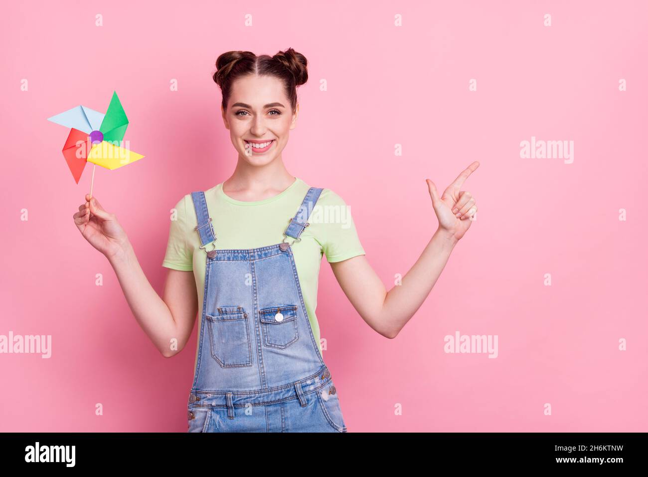 Photo of girl hold propeller toy indicate finger empty space wear jeans overall green t-shirt ...