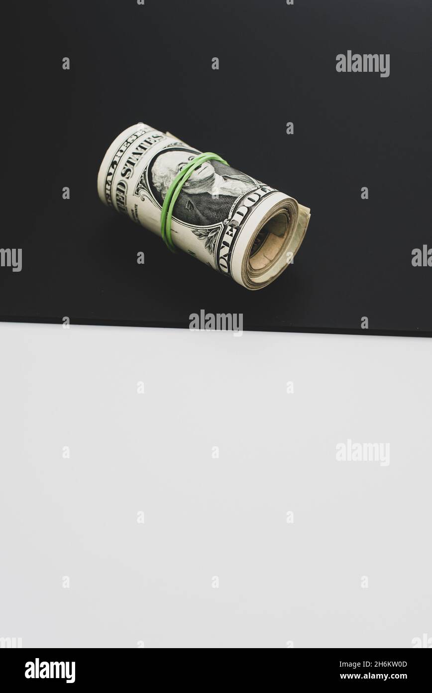 isolated US dollar banknotes roll on a white and black paper background ...