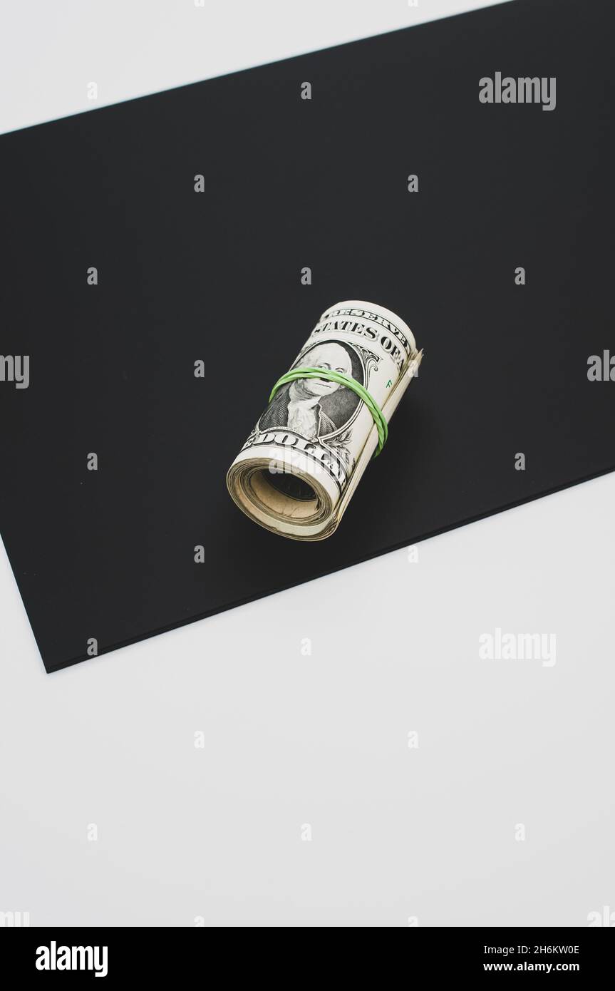 isolated US dollar banknotes roll on a white and black paper background ...