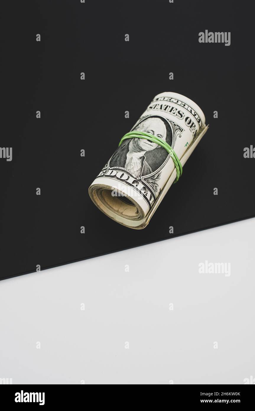 isolated US dollar banknotes roll on a white and black paper background ...