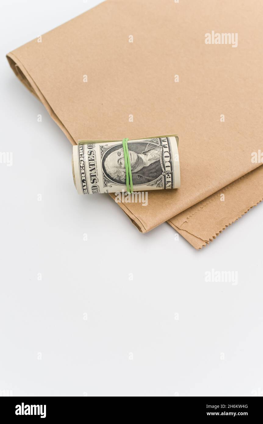 isolated US dollar banknotes roll on a white and brown paper background ...