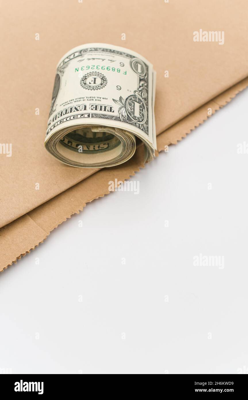isolated US dollar banknotes roll on a white and brown paper background ...
