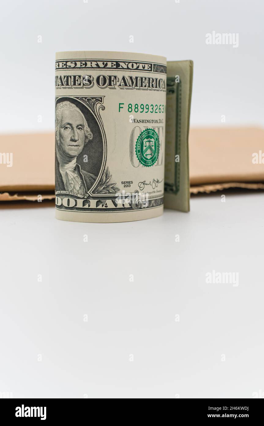 isolated US dollar banknotes roll on a white and brown paper background ...