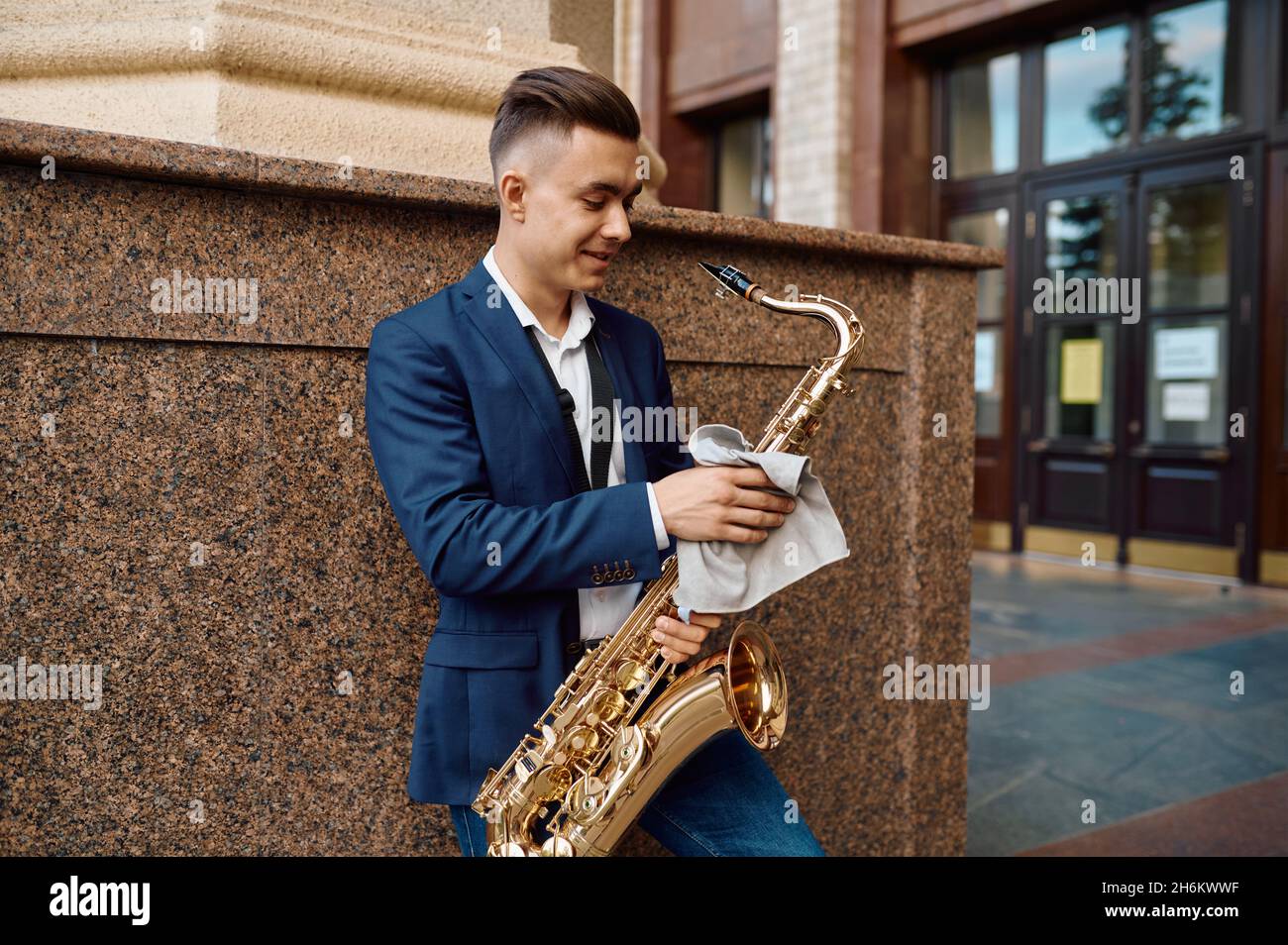 Male saxophonist poses with saxophone at building Stock Photo - Alamy