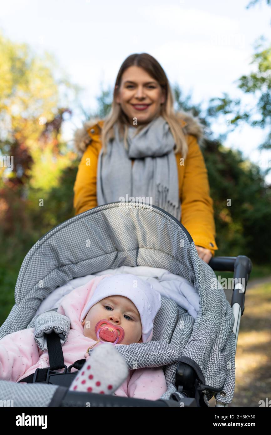 Picture of young cheerful caucasian lady walking her baby with a ...