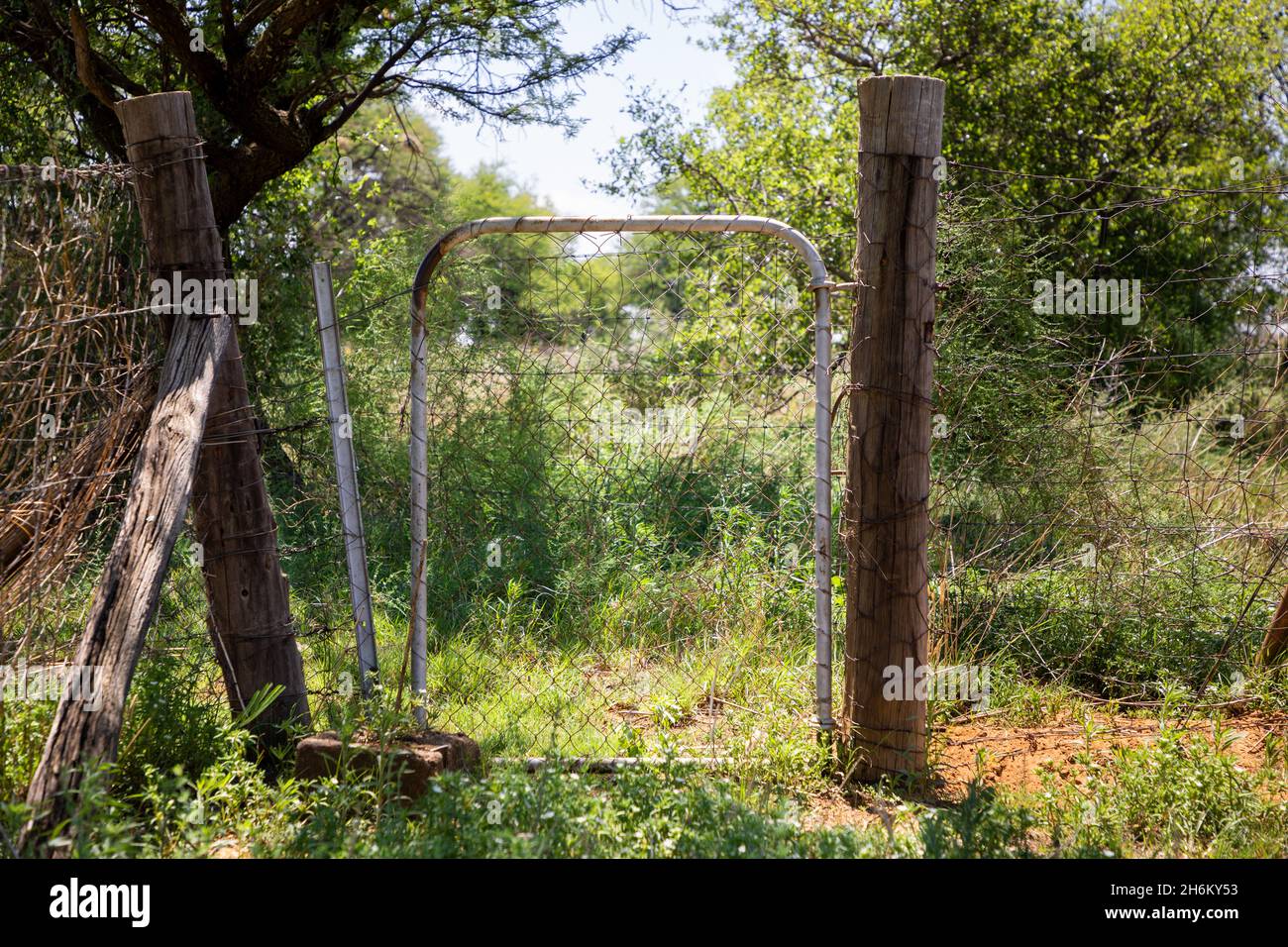 Metal pedestrian gate in a field, the gate is supported by wooden fence ...