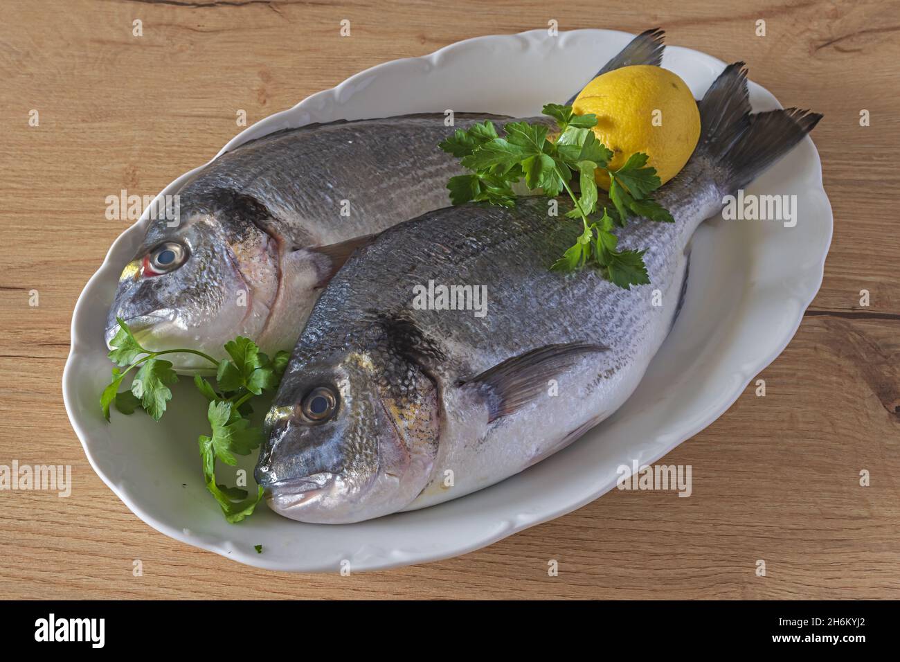 orate crude nel piatto con prezzemolo e limone 3 Stock Photo - Alamy