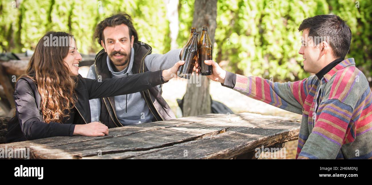 Cheers. Smiling cheerful young friends drinks beer from bottle on ...