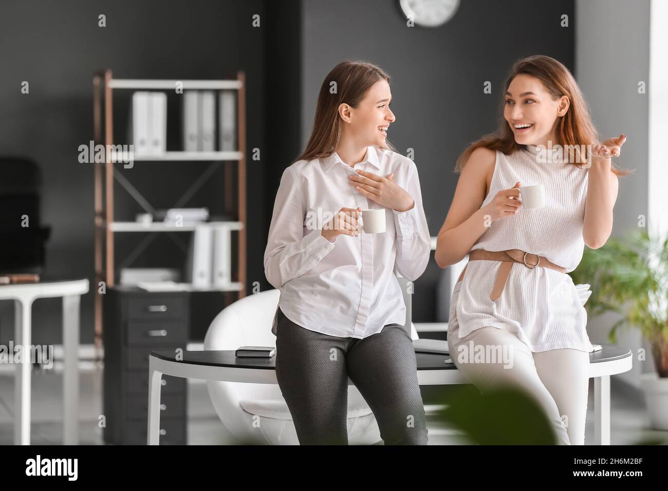 Female colleagues gossiping in office Stock Photo - Alamy