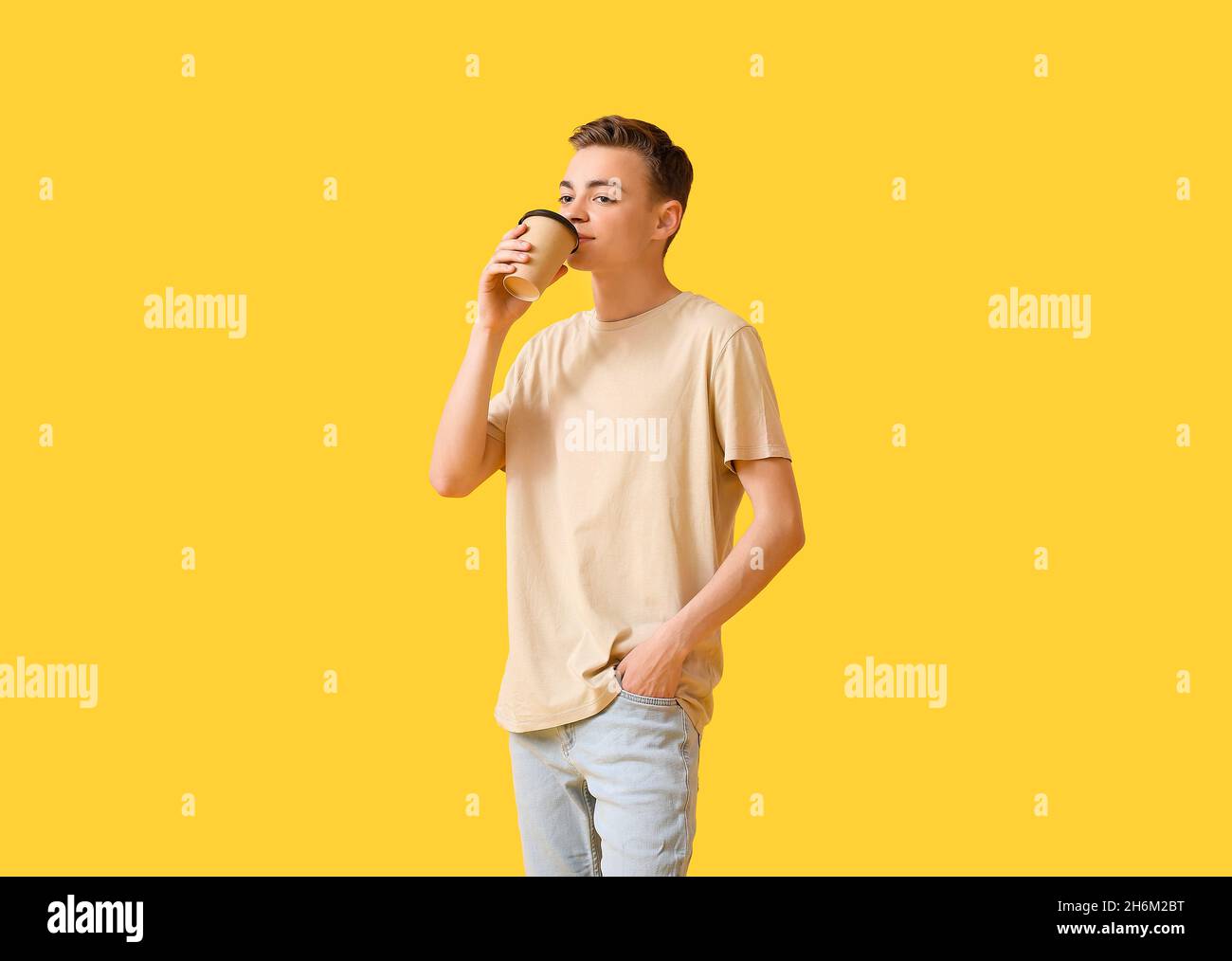 Teenage boy drinking coffee on yellow background Stock Photo - Alamy