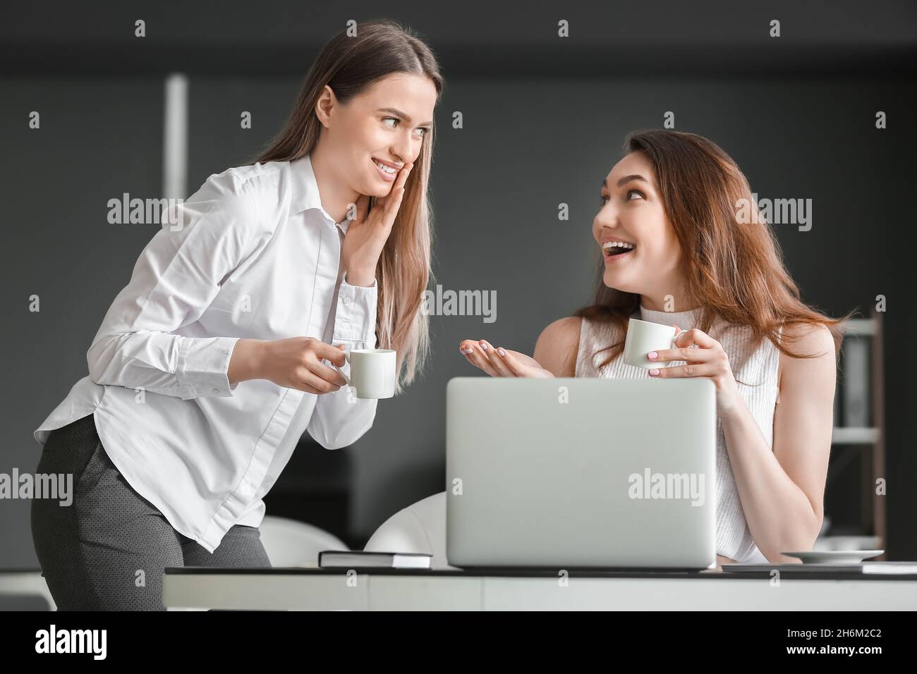Female colleagues gossiping in office Stock Photo - Alamy