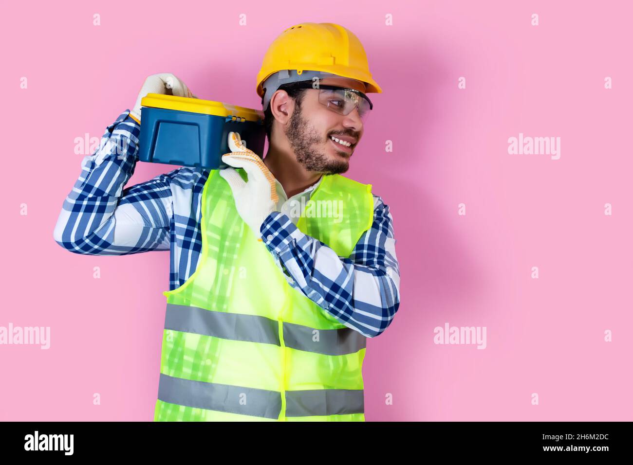 Closeup of the worker with helmet holding construction box on pink ...