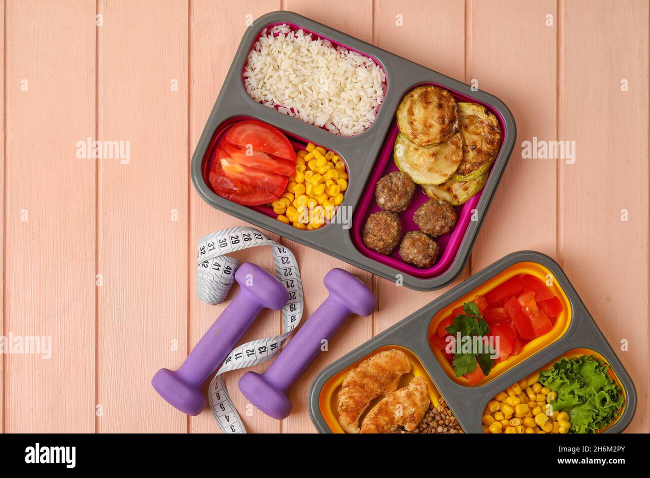 Containers with healthy food, dumbbells and measuring tape on color ...