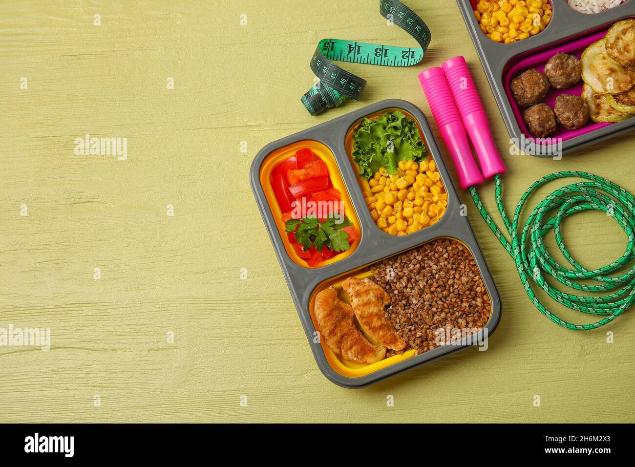 Containers with healthy food, skipping rope and measuring tape on color ...