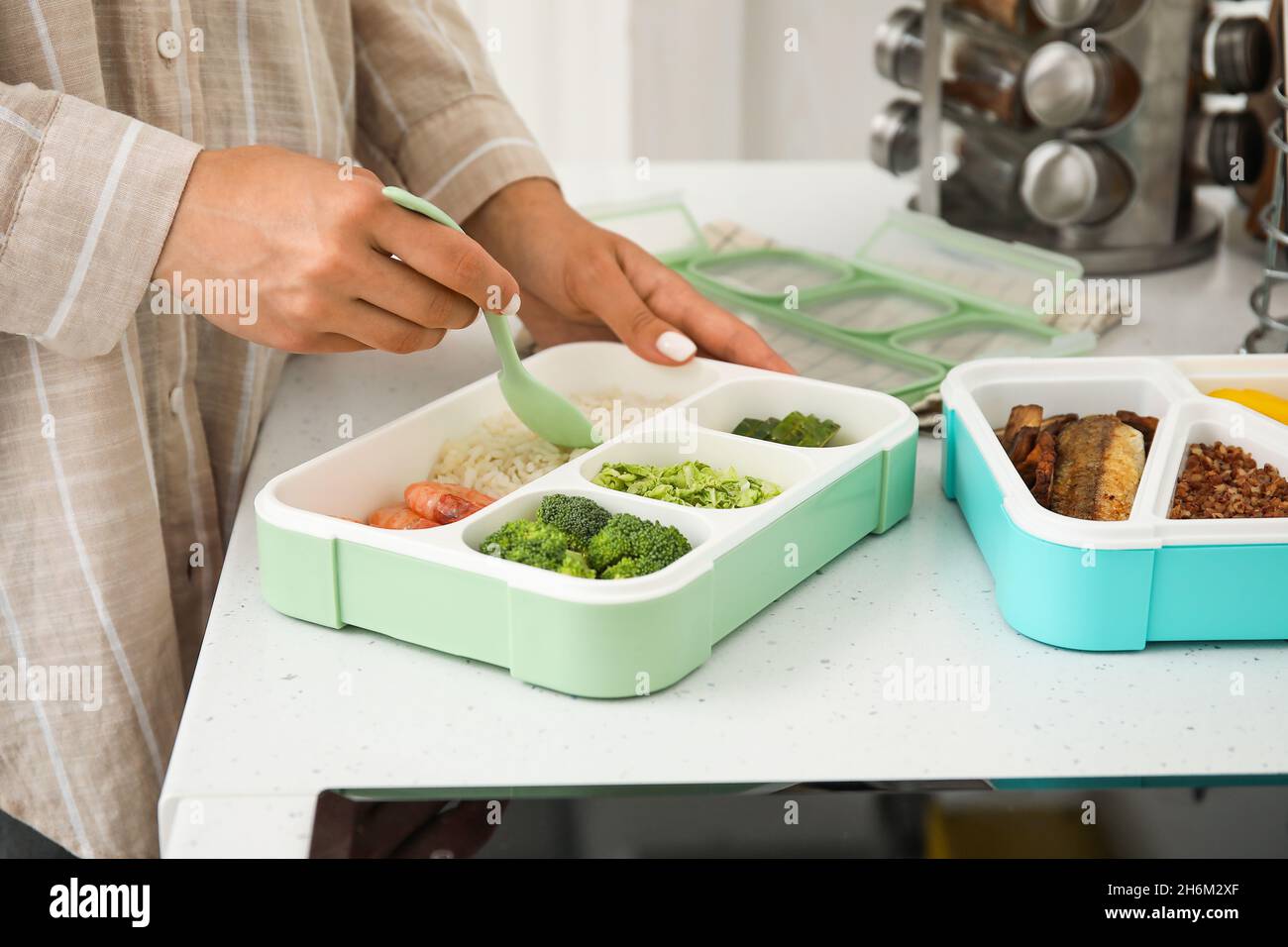 Young woman packing delicious healthy meal into containers on table in ...