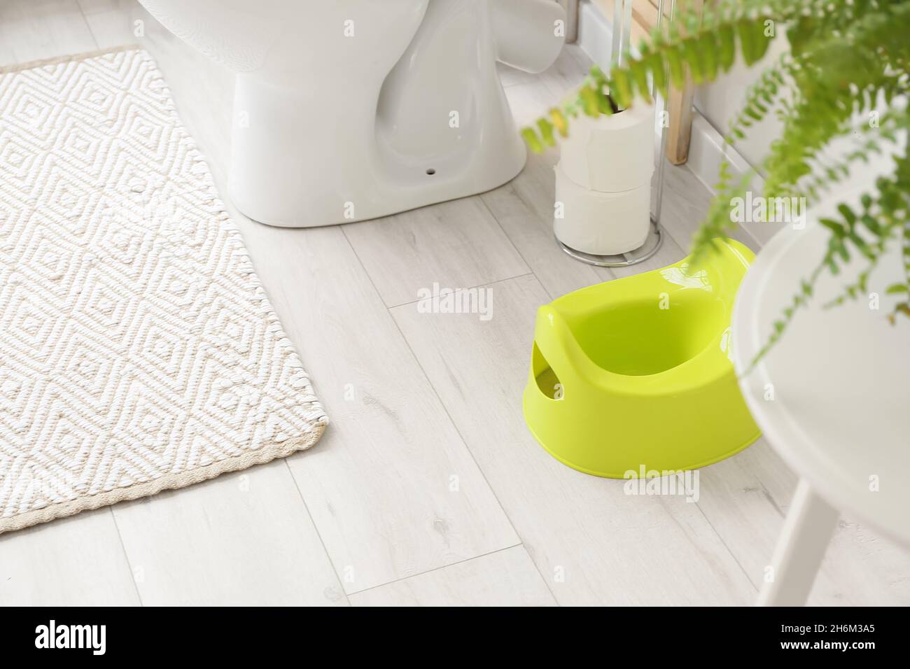 Green potty on light wooden floor in restroom Stock Photo - Alamy