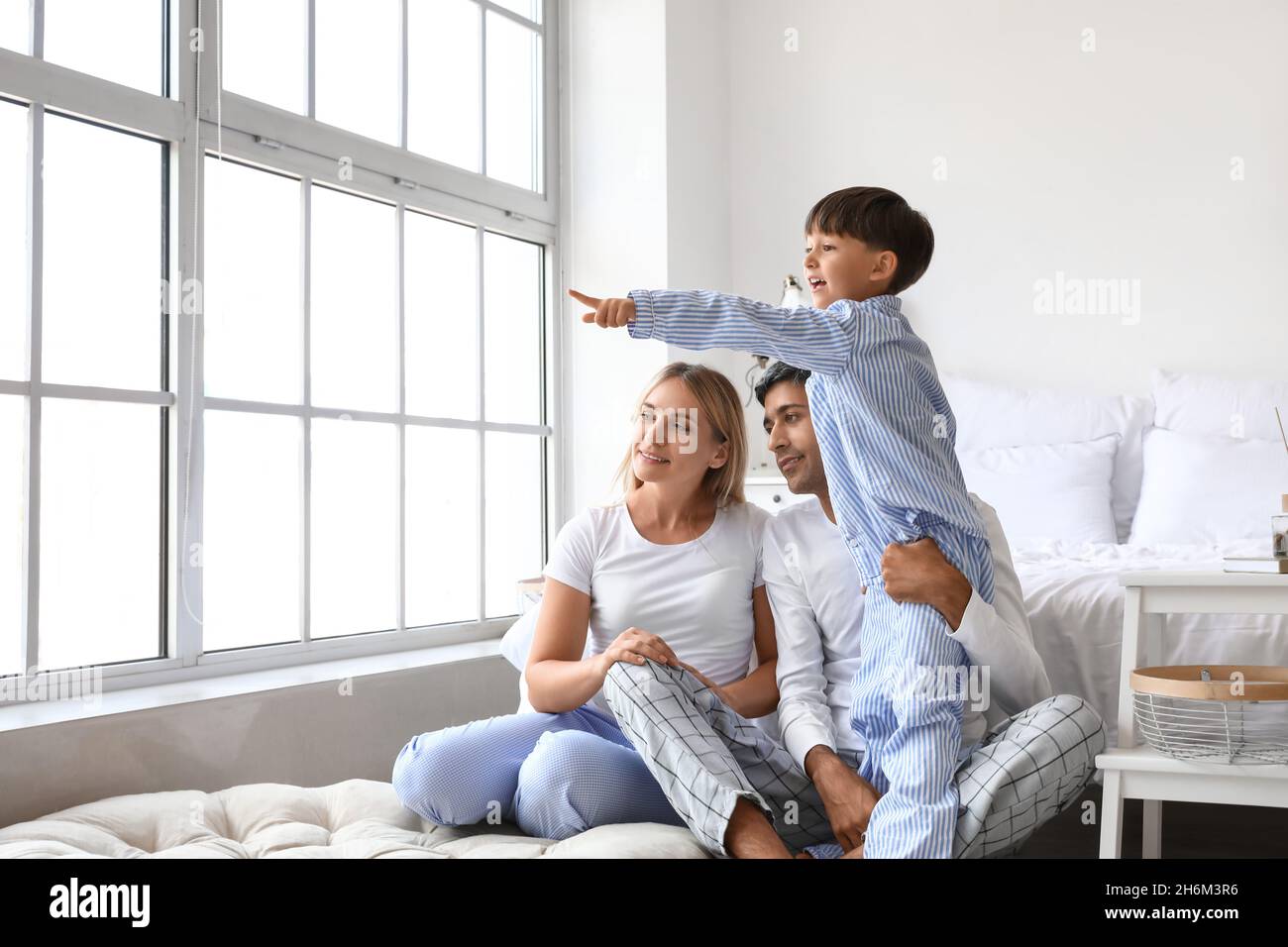 Little boy pointing at something to his parents in bedroom Stock Photo ...