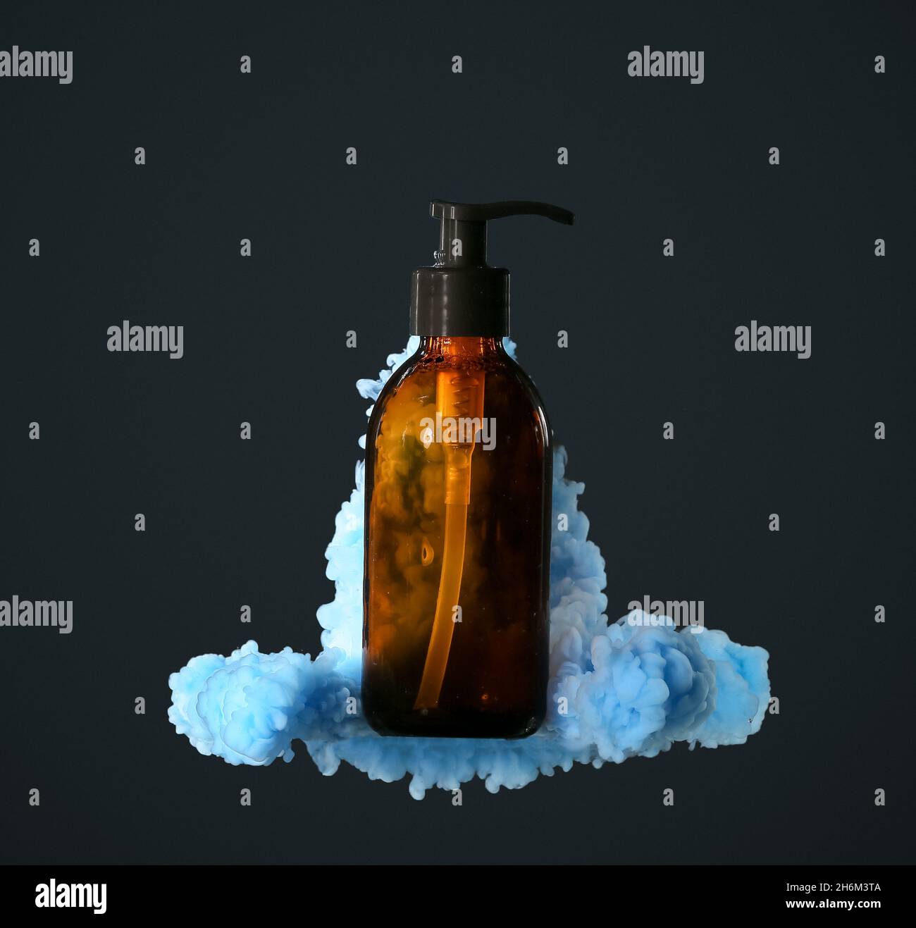 Bottle of cosmetic product in blue smoke on dark background Stock Photo ...