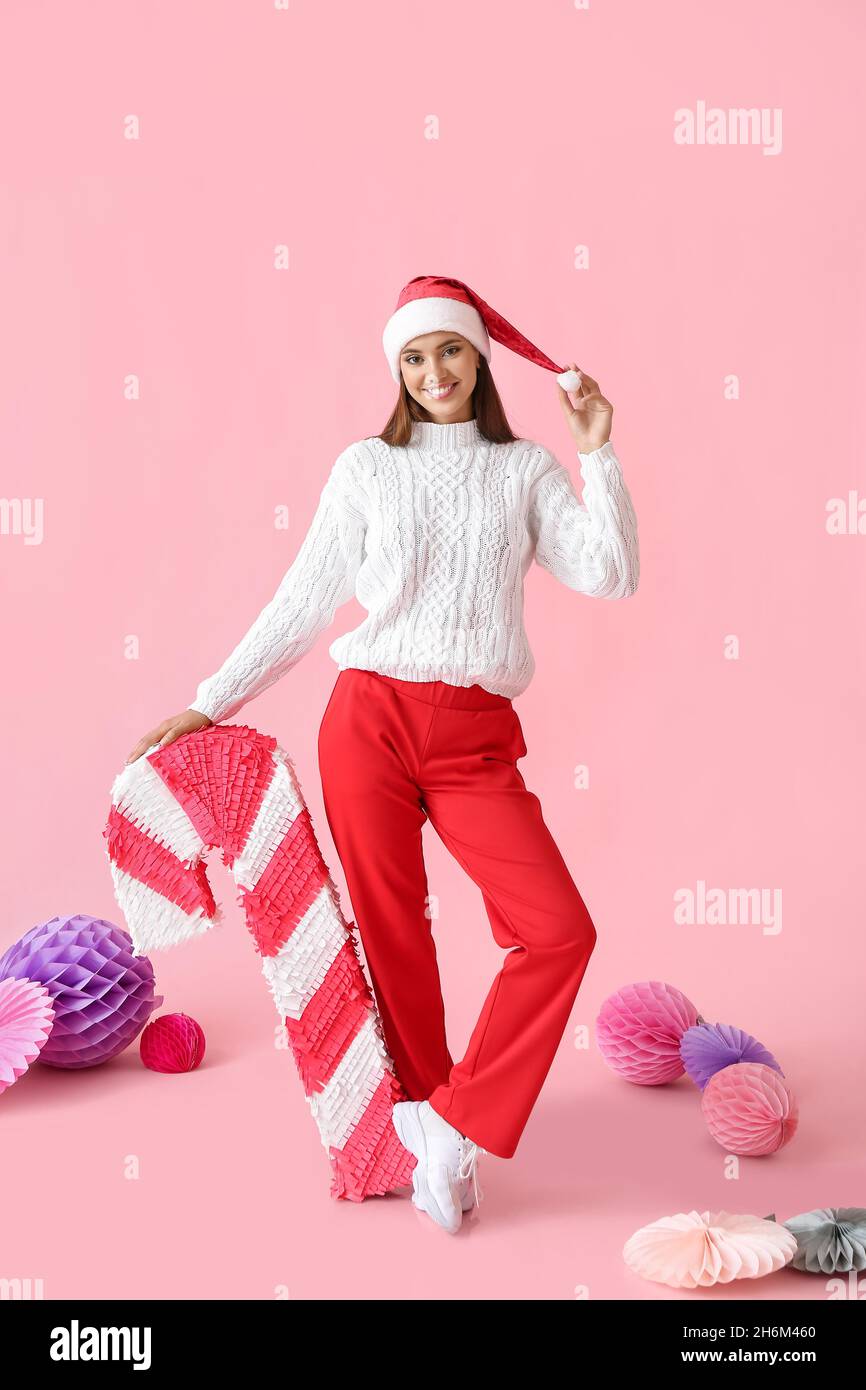 Beautiful woman in Santa hat and with candy cane pinata on color ...