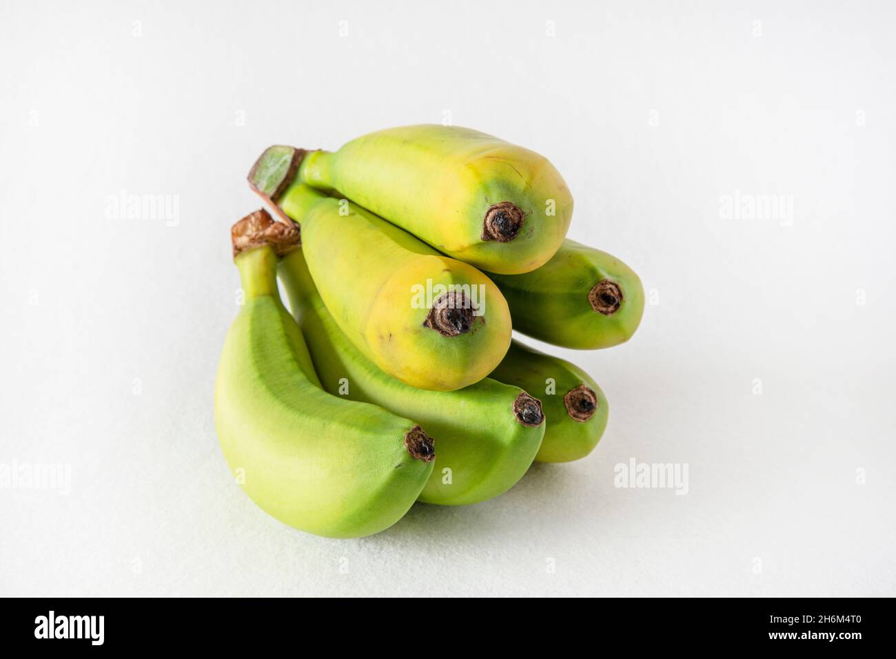 Small yellow and green bananas on a white background Stock Photo - Alamy