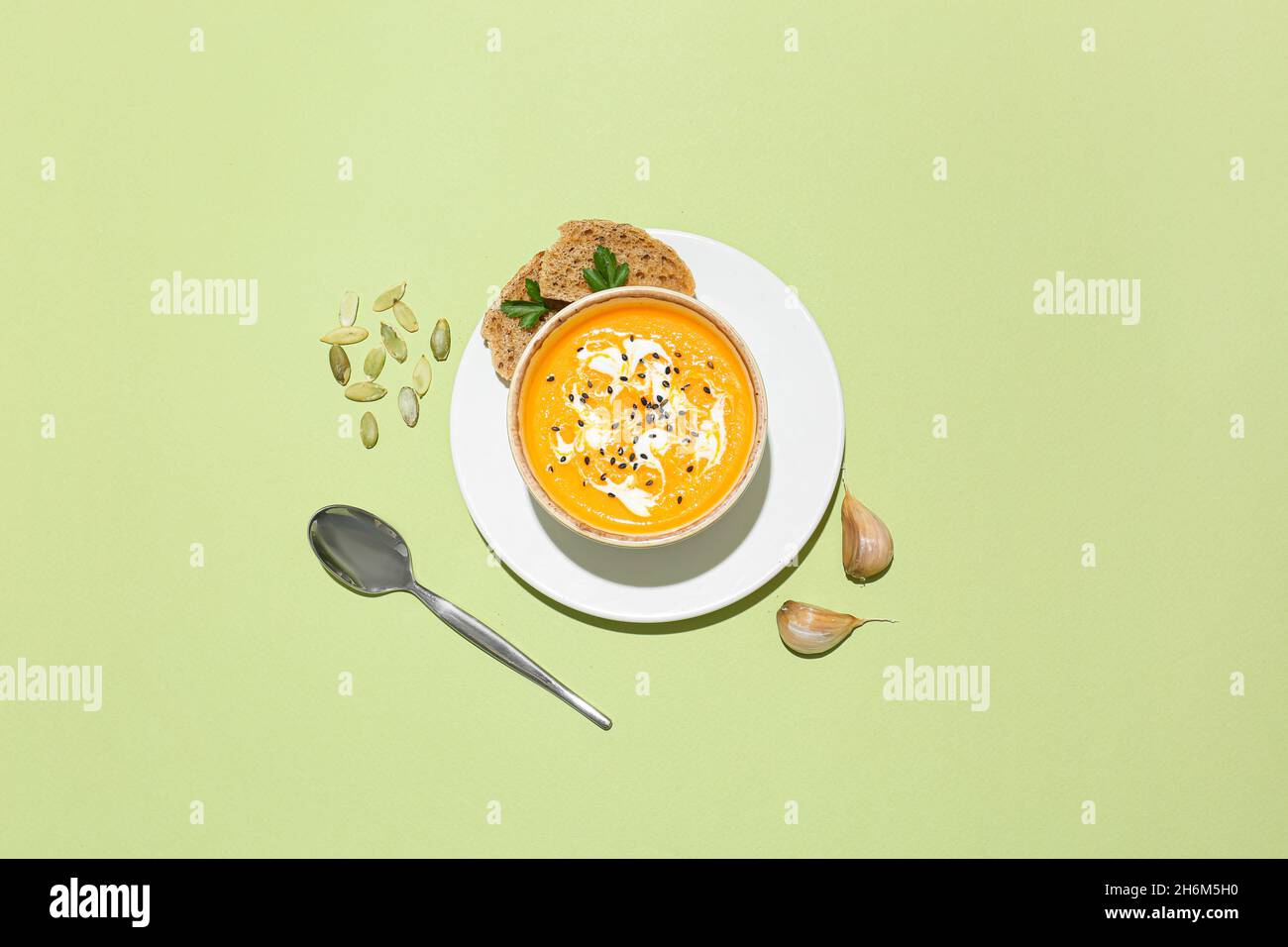 Bowl with delicious pumpkin cream soup and seeds on color background ...