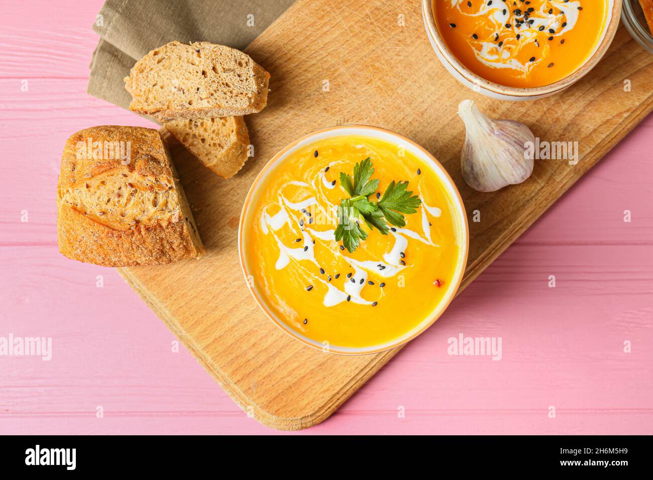 Bowls with delicious pumpkin cream soup and bread on color wooden ...