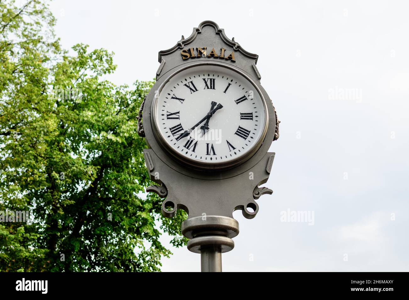 Vintage style grey metallic clock towards cloudy sky in Sinaia Park ...