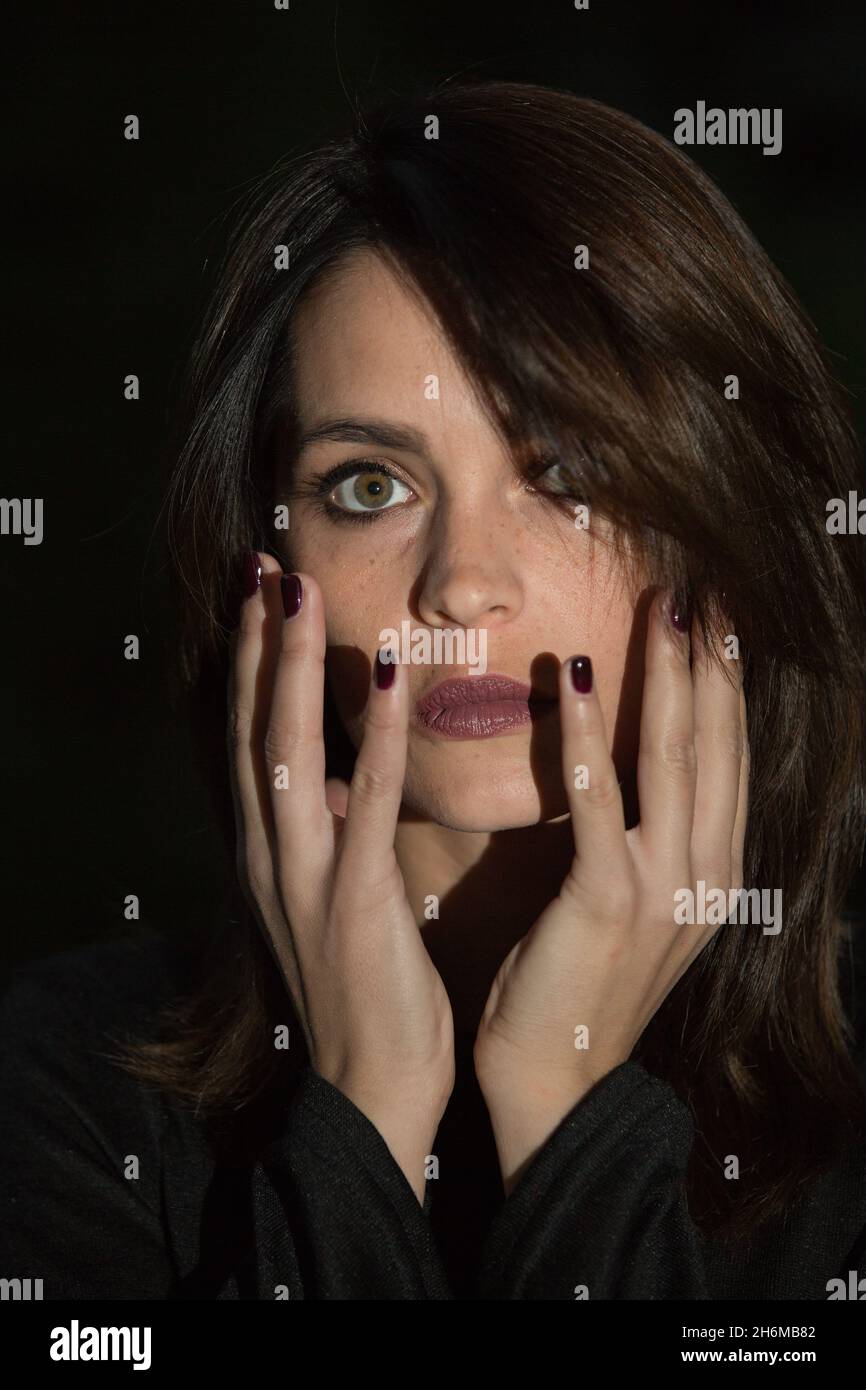 Face of a beautiful young woman. The girl covers part of her face with ...