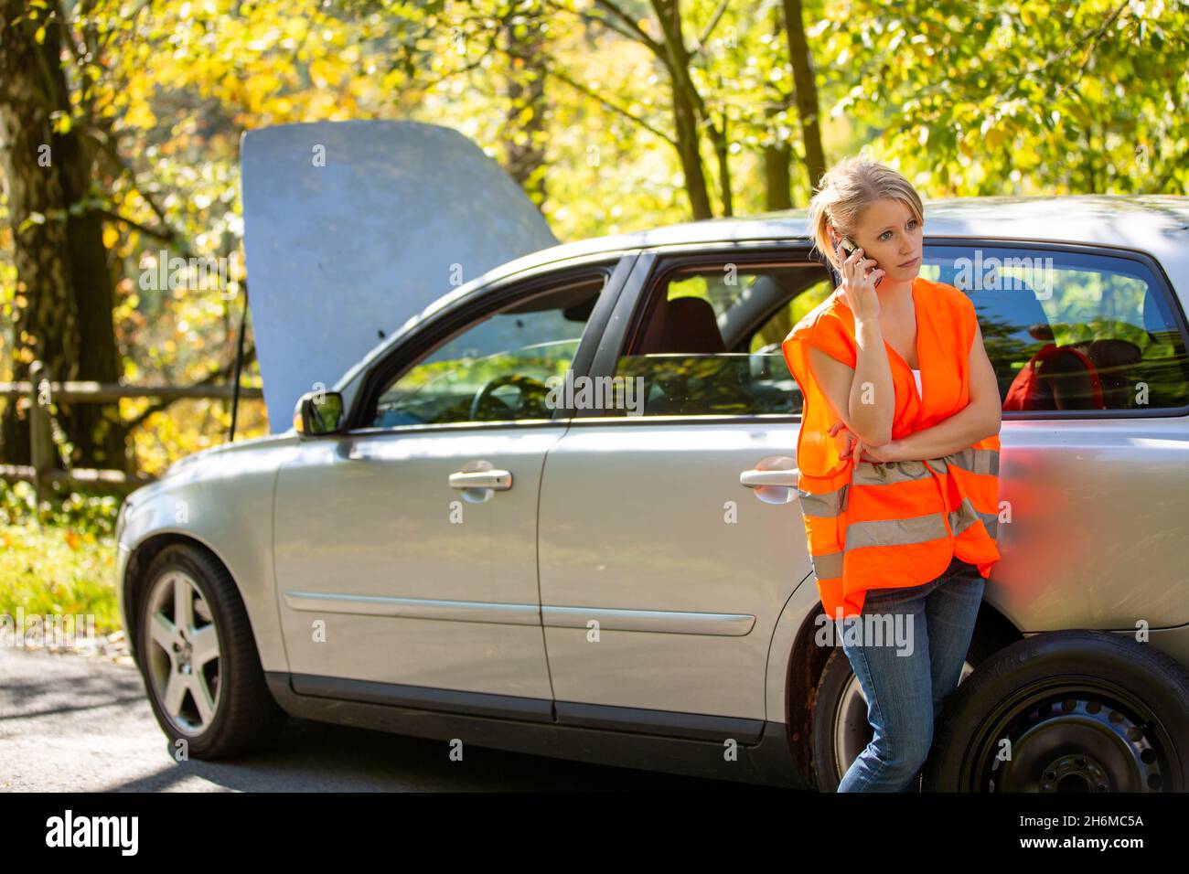 Young female driver wearing a high visibility vest, calling the ...