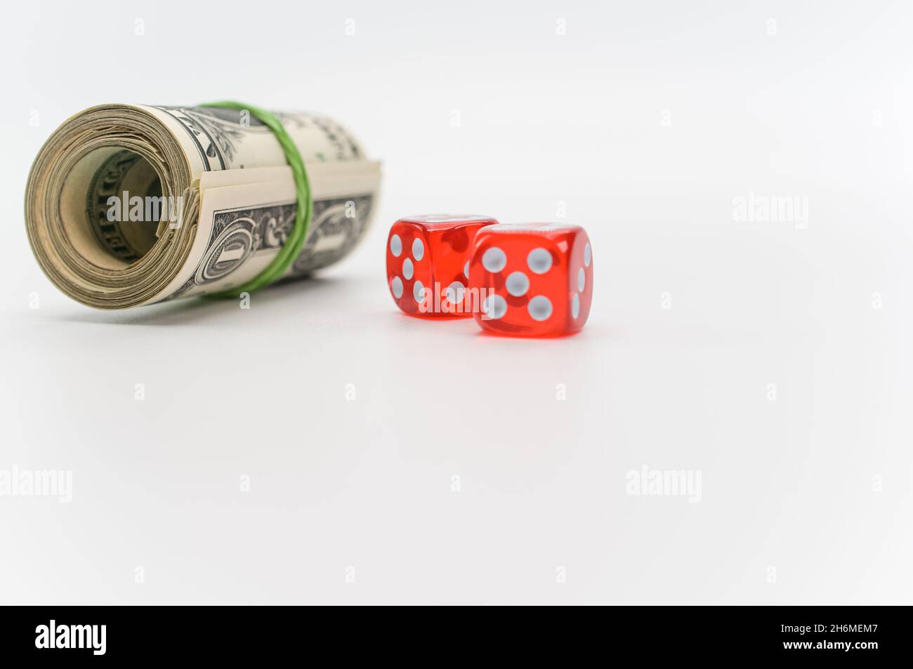 red dice and isolated US dollar banknotes roll on a white background ...