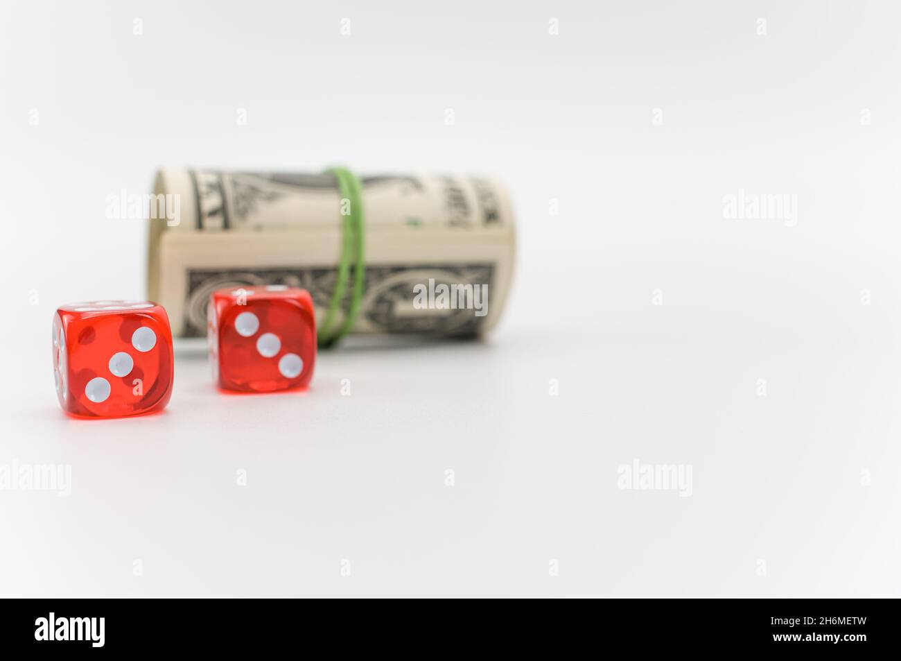 red dice and isolated US dollar banknotes roll on a white background ...