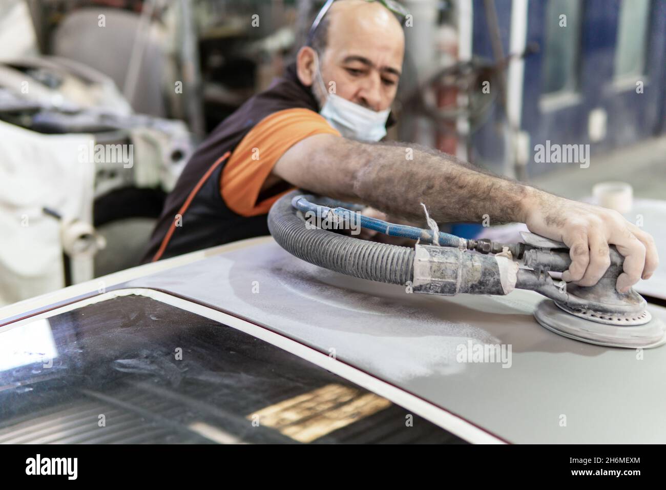Auto mechanic sanding a part of a car in a garage. Preparing for Stock ...