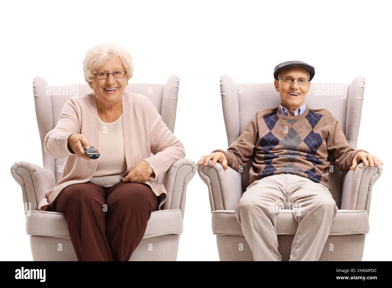 Elderly couple sitting in an armchairs and holding a tv remote control ...